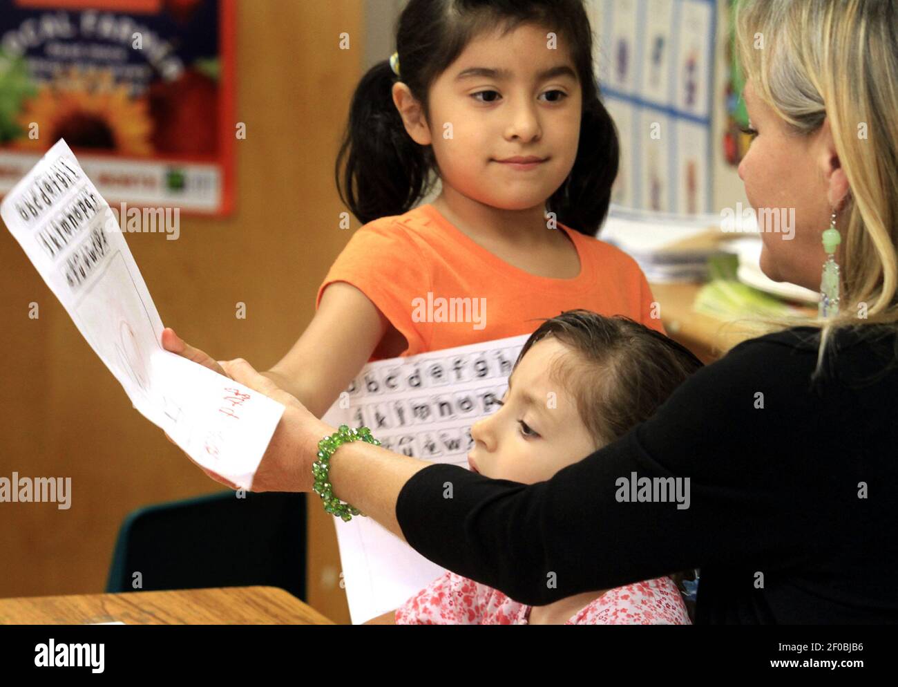 Kristi Dunning checks the work of two of her kindergarteners at Ann Soldo Elementary School in ...