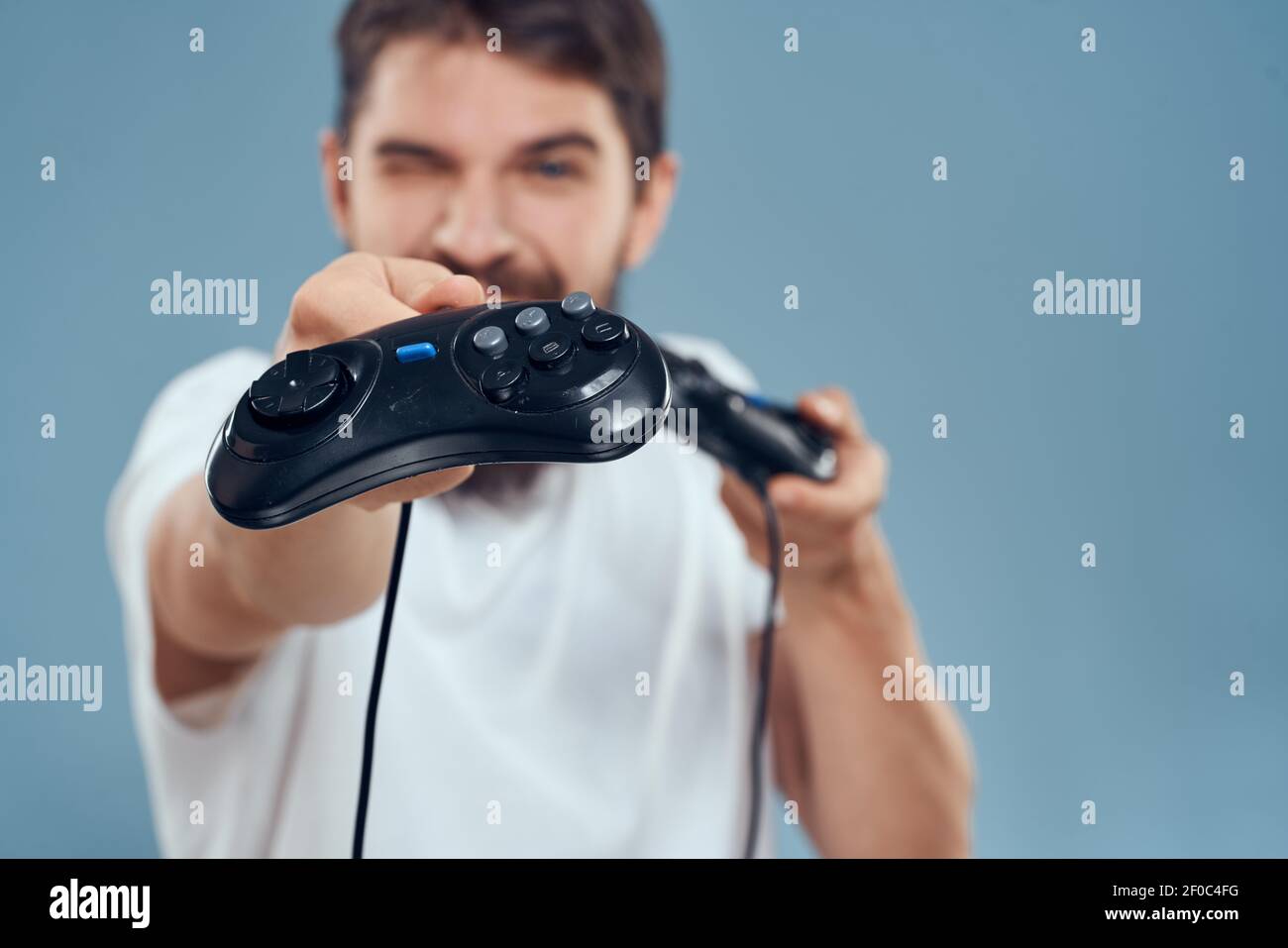 a man in a white t-shirt with a joystick in his hands game console ...