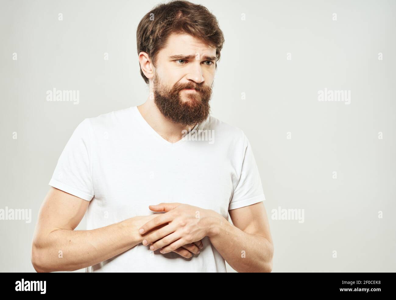 Guy in a white T-shirt on a light background emotions sad face cropped ...