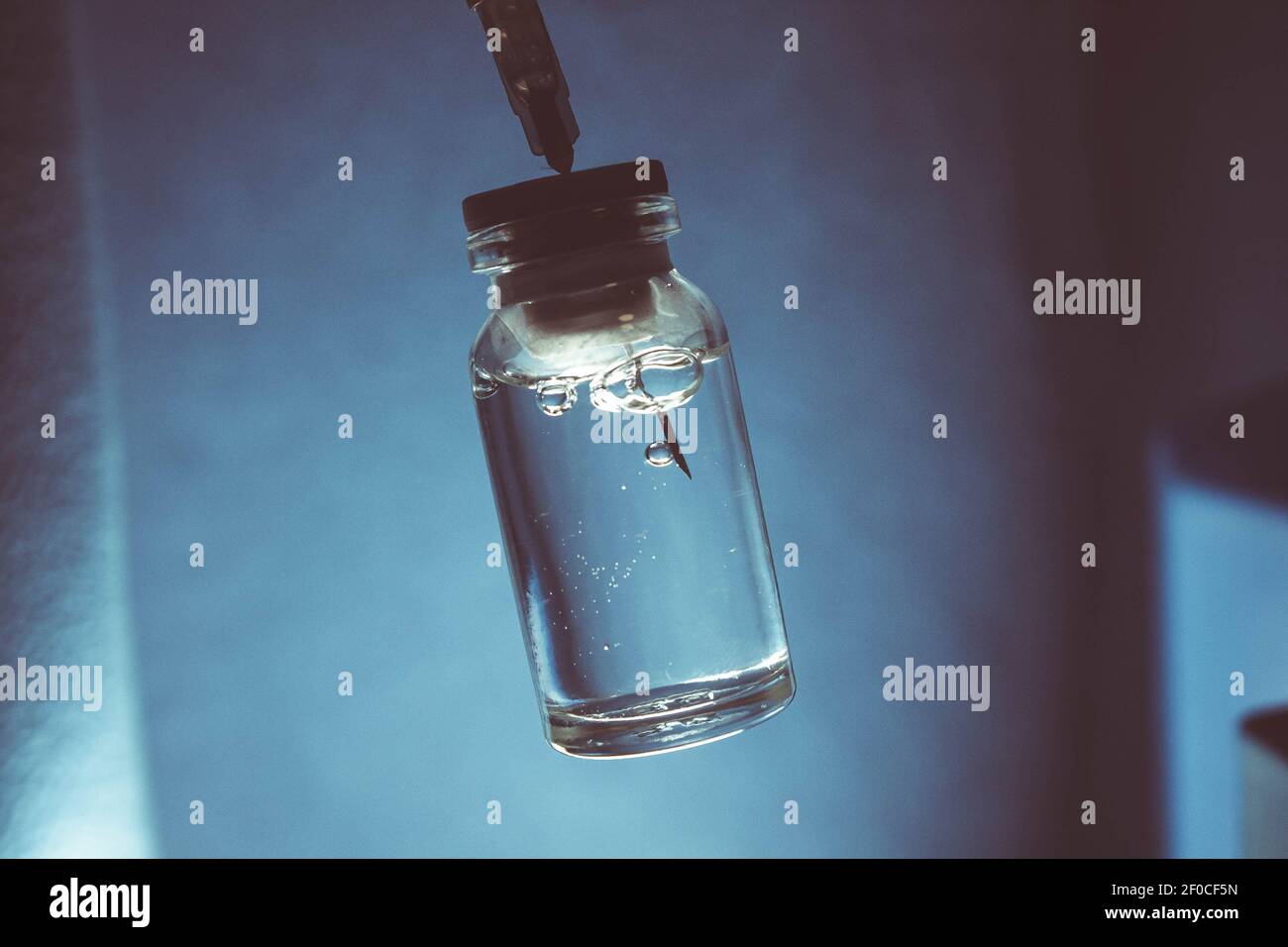 Vaccine in vitro. Medicine in a flask on a blue background. Antibiotic ...