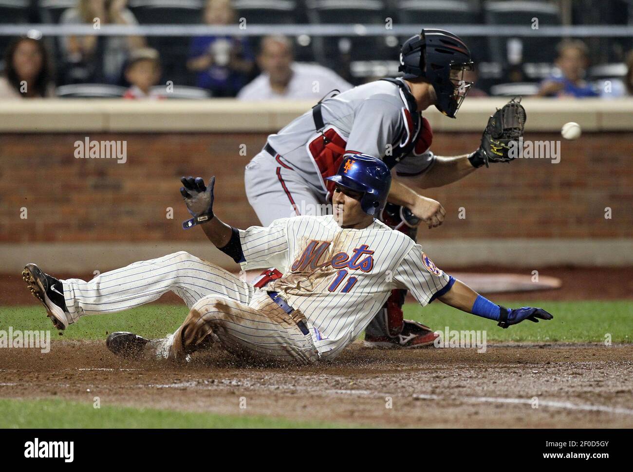 The New York Mets' Ruben Tejada (11) slides home safely ahead of the ...
