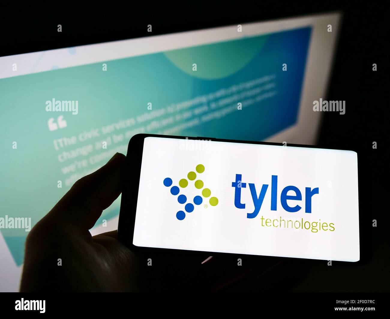 Person holding cellphone with logo of US software company Tyler ...