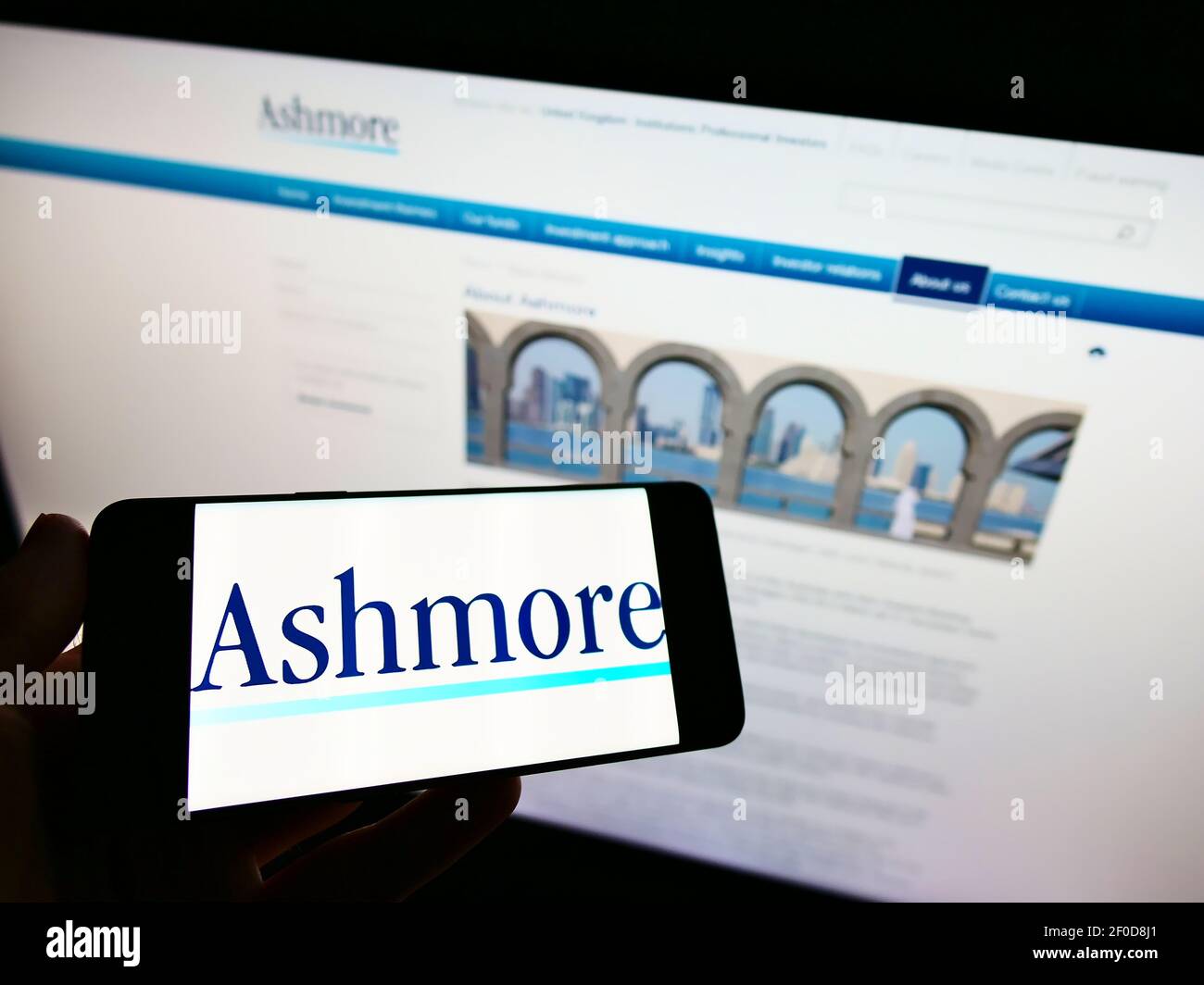Person holding cellphone with business logo of British investment manager Ashmore Group plc on ...