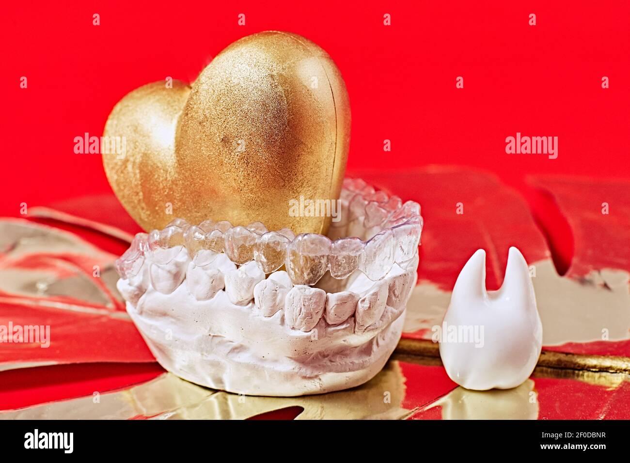 Heart of gold on a red background in invisible dental aligners or ...