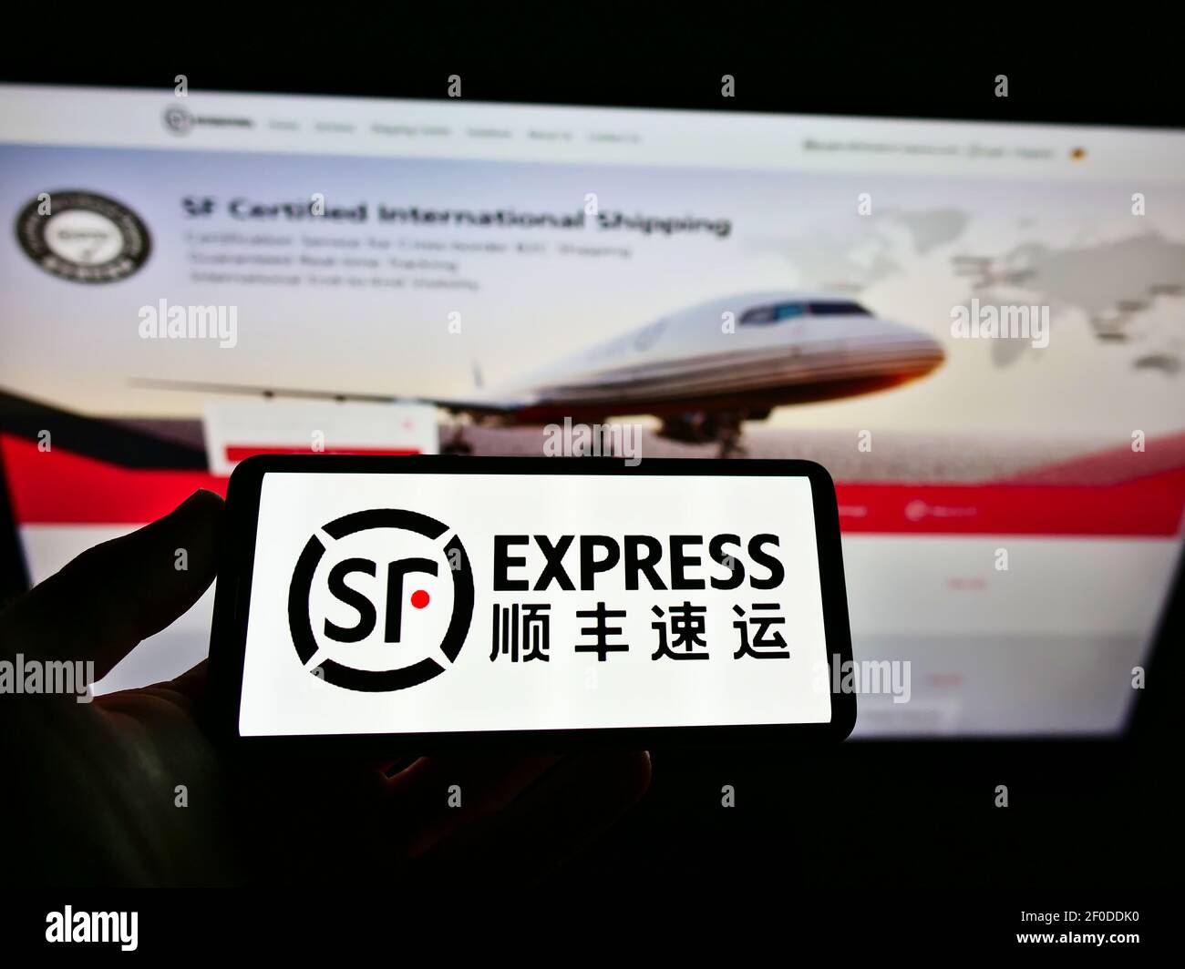 Person holding mobile phone with logo of Chinese logistics company SF ...