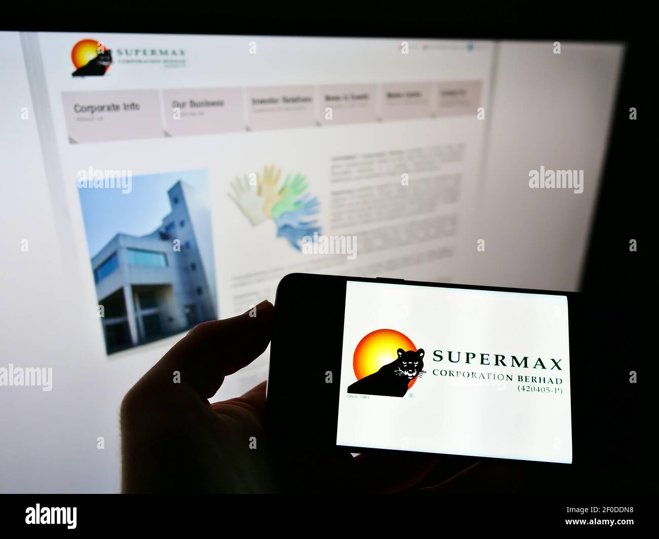 Person holding smartphone with logo of Malaysian gloves producer ...