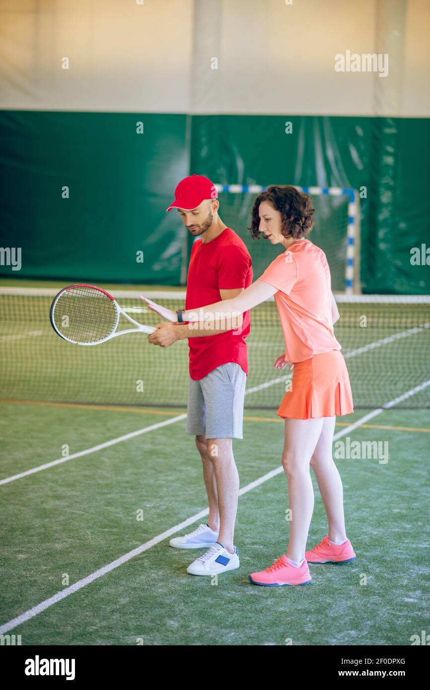 Man in a red cap and with a racket having a workout with his coach ...