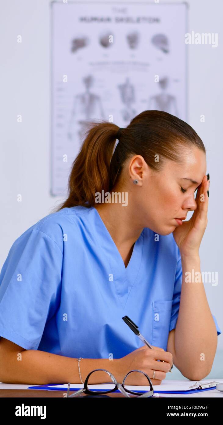Tired healthcare medical assistant working in hospital researching ...