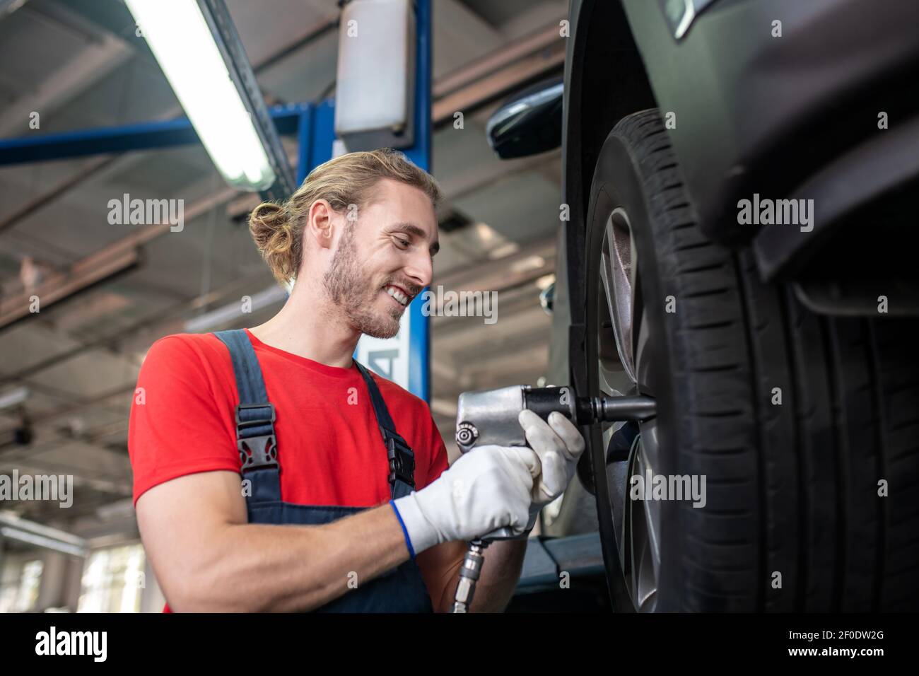 Satisfied man near wheel of car being repaired Stock Photo - Alamy
