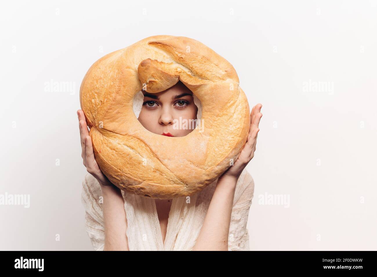 beautiful woman with a round loaf of bread in her hands on a light ...