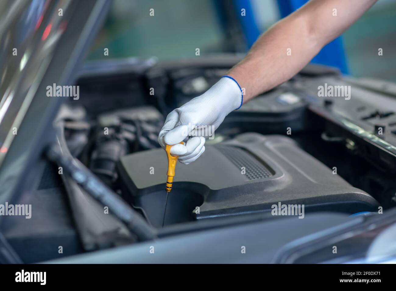 Male hand lowering dipstick measuring oil level Stock Photo - Alamy