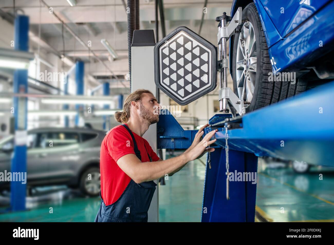 Serious repairman standing near car being repaired Stock Photo - Alamy