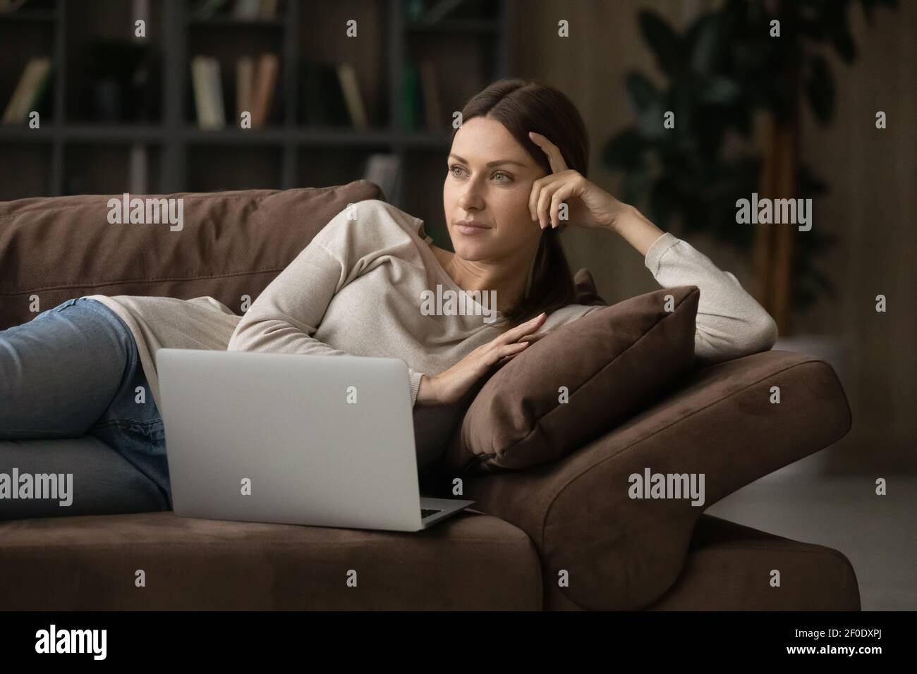 Pensive young woman distracted from computer thinking Stock Photo - Alamy