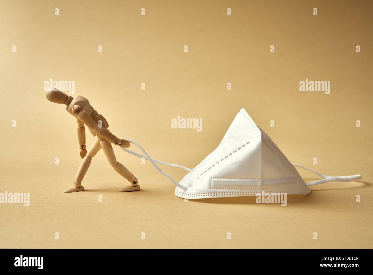 Tired wooden person dragging a white FFP2 or KN95 respirator, destined ...