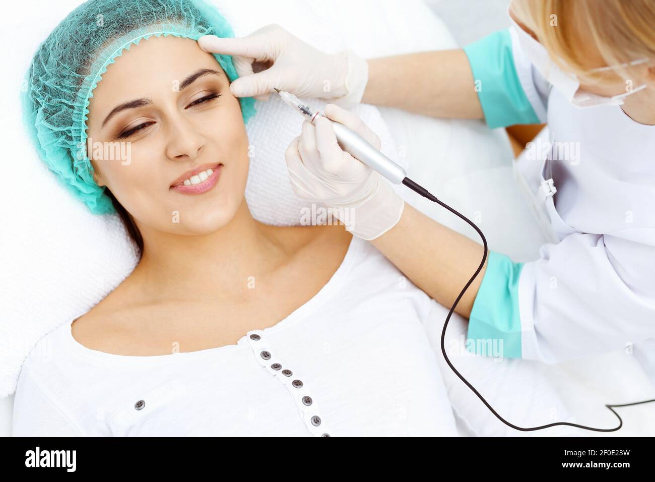 Professional beautician doing eyebrow tattoo at woman face. Permanent ...
