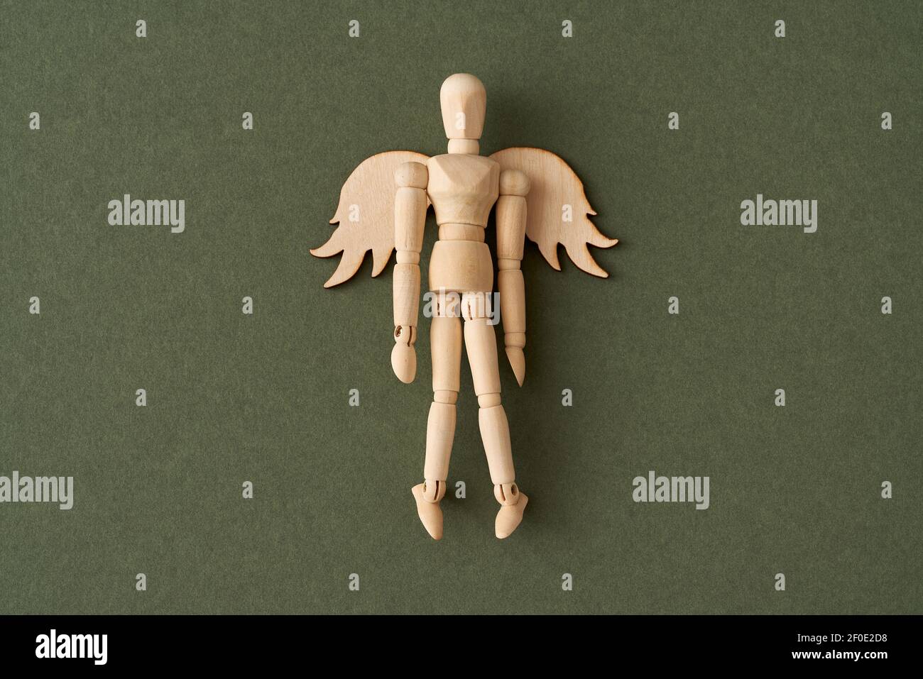 Wooden figure with wings lying on a green paper background Stock Photo ...