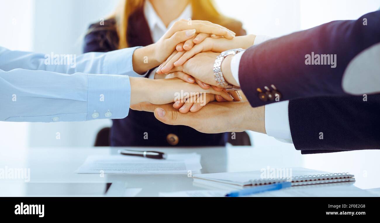 Business team showing unity with their hands together in sunny office ...