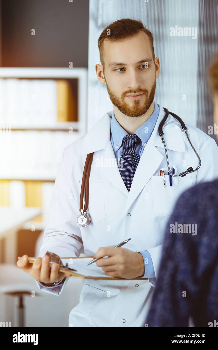 Friendly red-bearded doctor and patient woman discussing current health ...