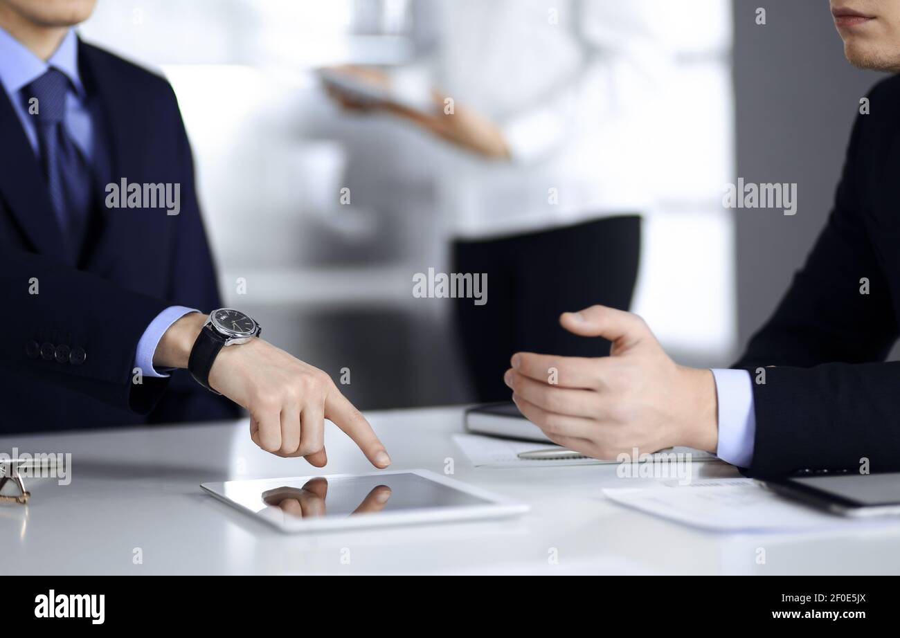Business people use a tablet computer for discussion of their new ...