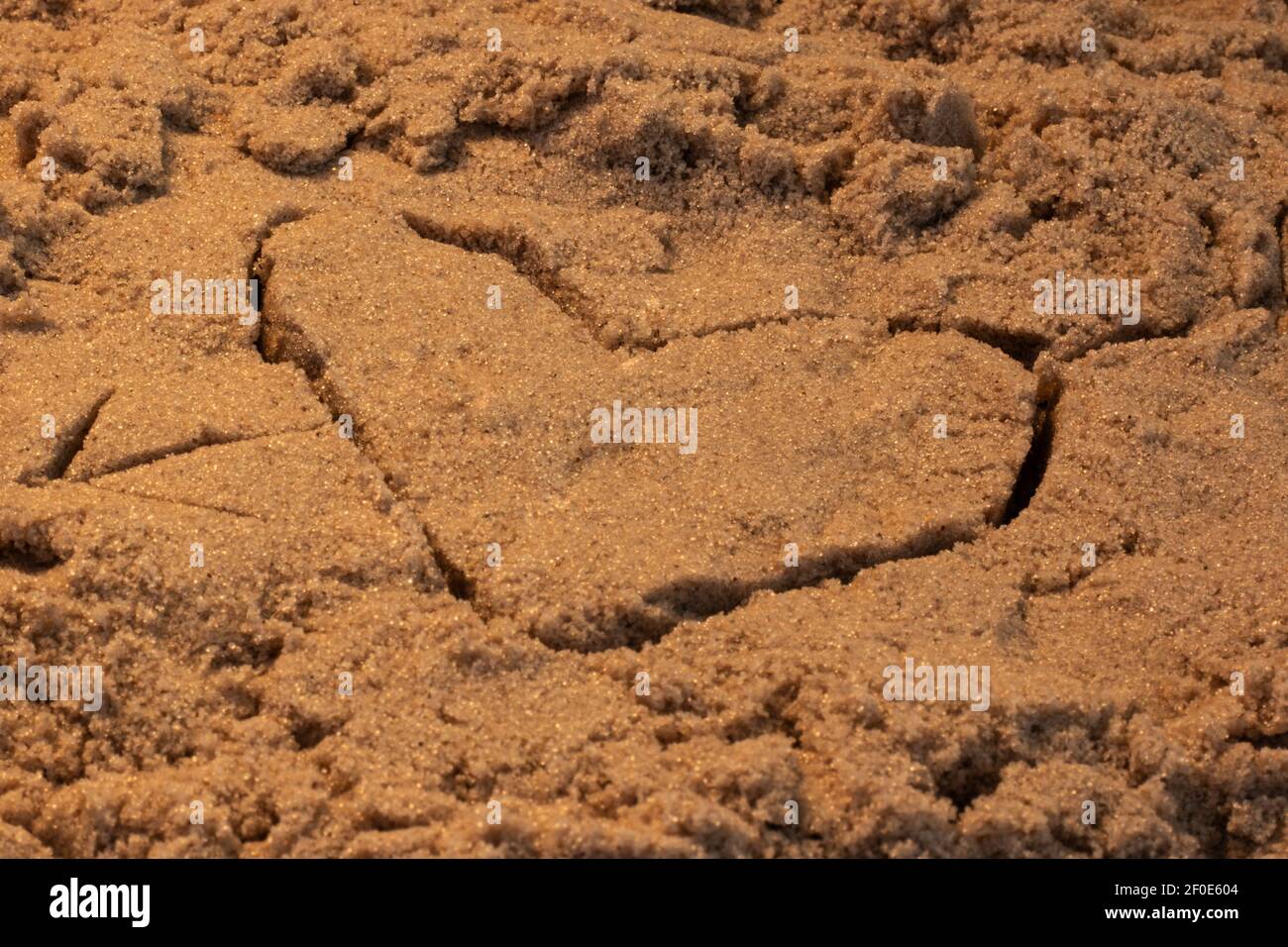 heart with an arrow through it drawn into kinetic sand under warm ...