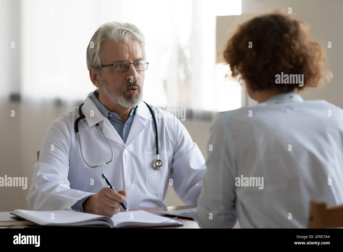 Mature male doctor talk with patient in hospital Stock Photo - Alamy