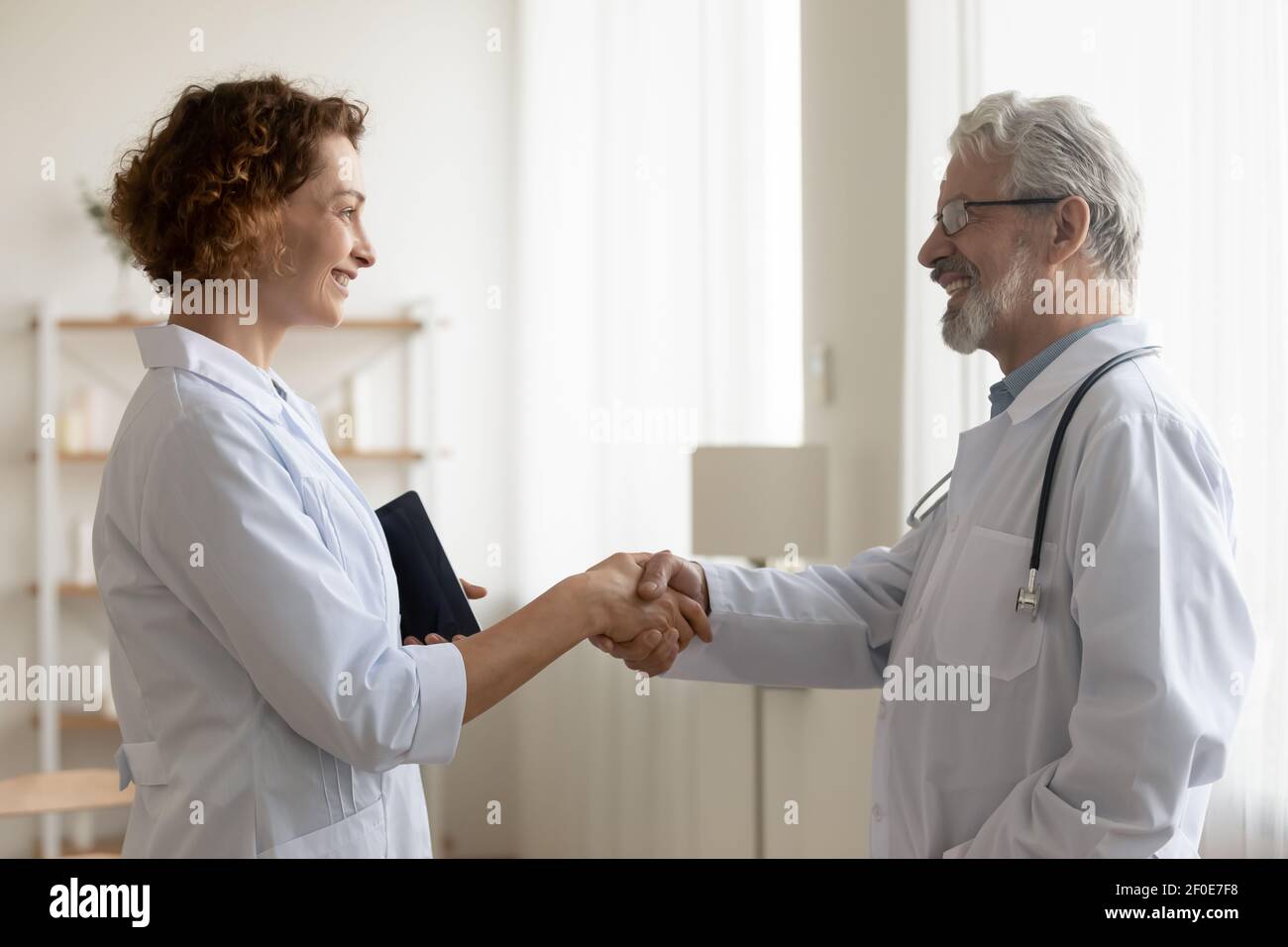 Happy doctors shake hands greeting in hospital Stock Photo - Alamy