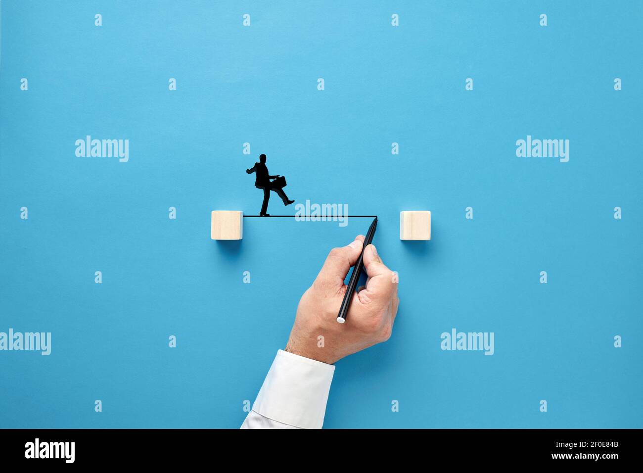 Businessman hand drawing a bridge line between wooden blocks for a ...