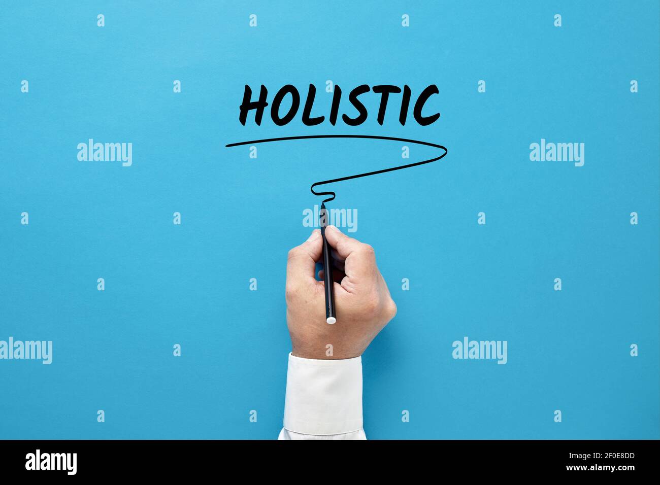 Businessman hand writing the business buzzword holistic on blue ...