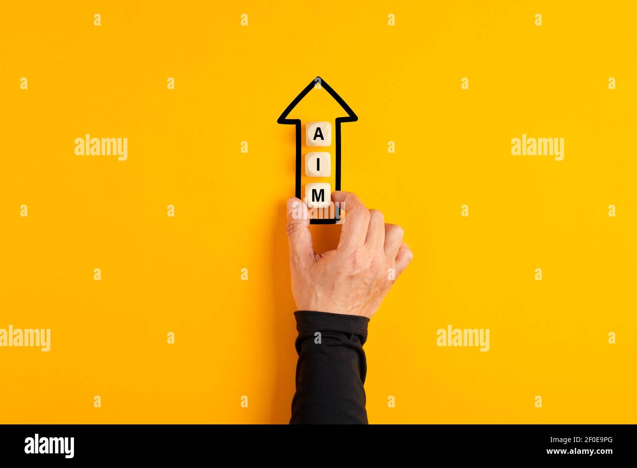 Male hand placing the wooden blocks with the word aim in an arrow ...