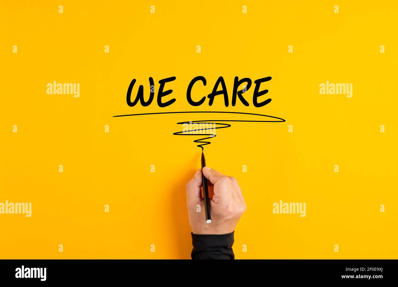 Male hand writing the message we care on yellow background. Customer ...