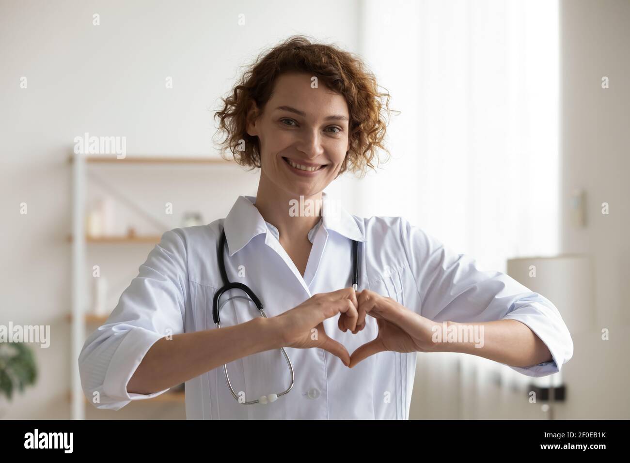 Portrait of smiling female doctor show love sign Stock Photo - Alamy