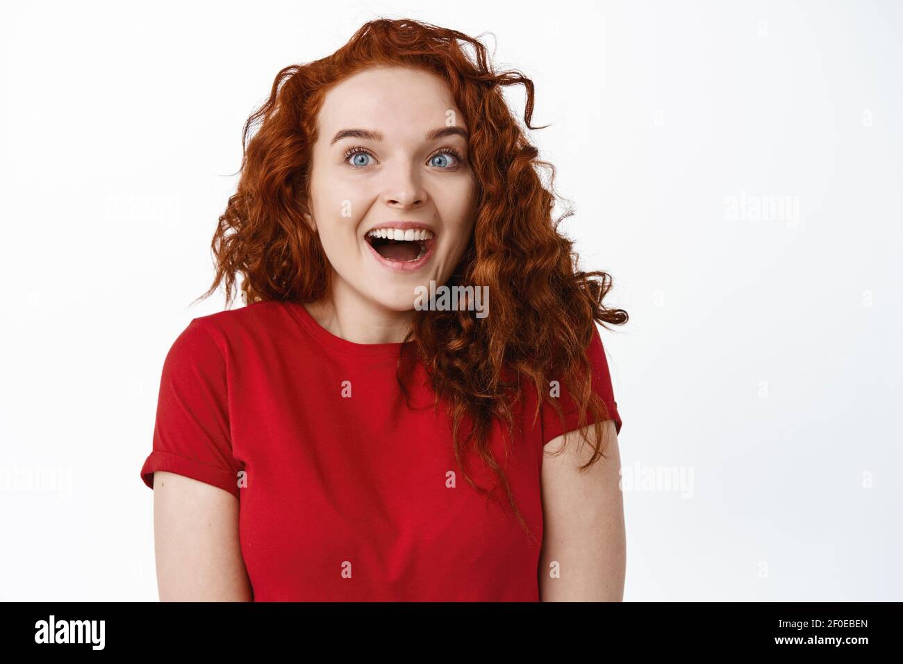 Close-up of excited happy ginger girl gasping fascinated, looking aside ...