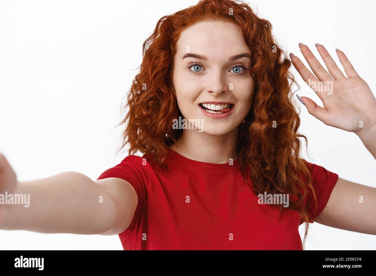 Close up of friendly ginger girl saying hello on video chat, waving ...