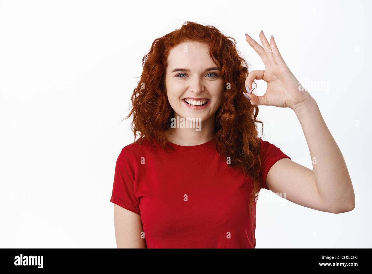 Well done. Smiling confident teen ginger girl showing OK sign, approve ...