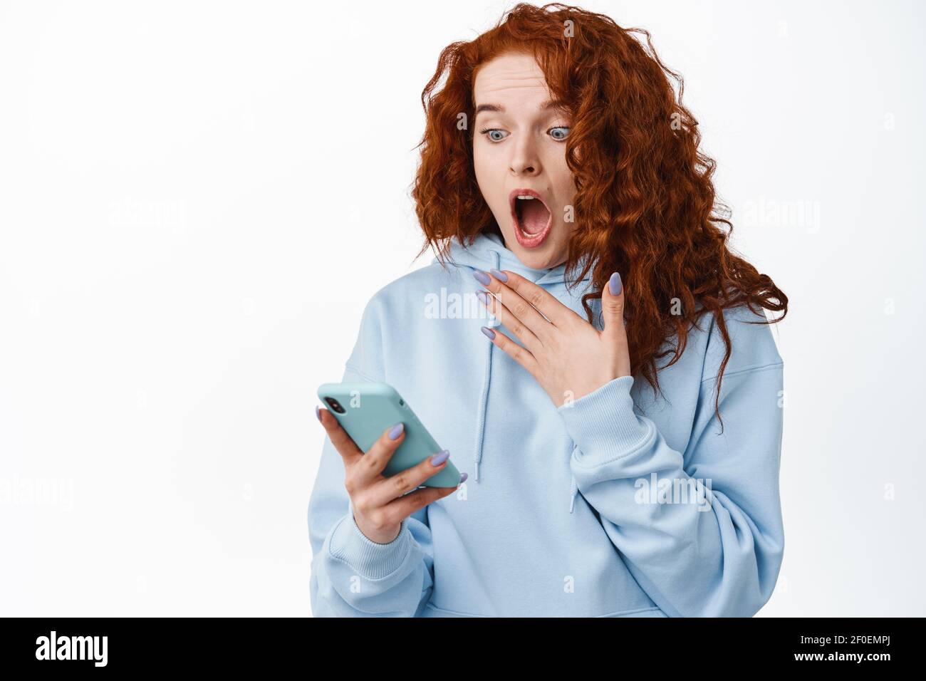 Shocked and startled redhead girl scream while reading message on ...