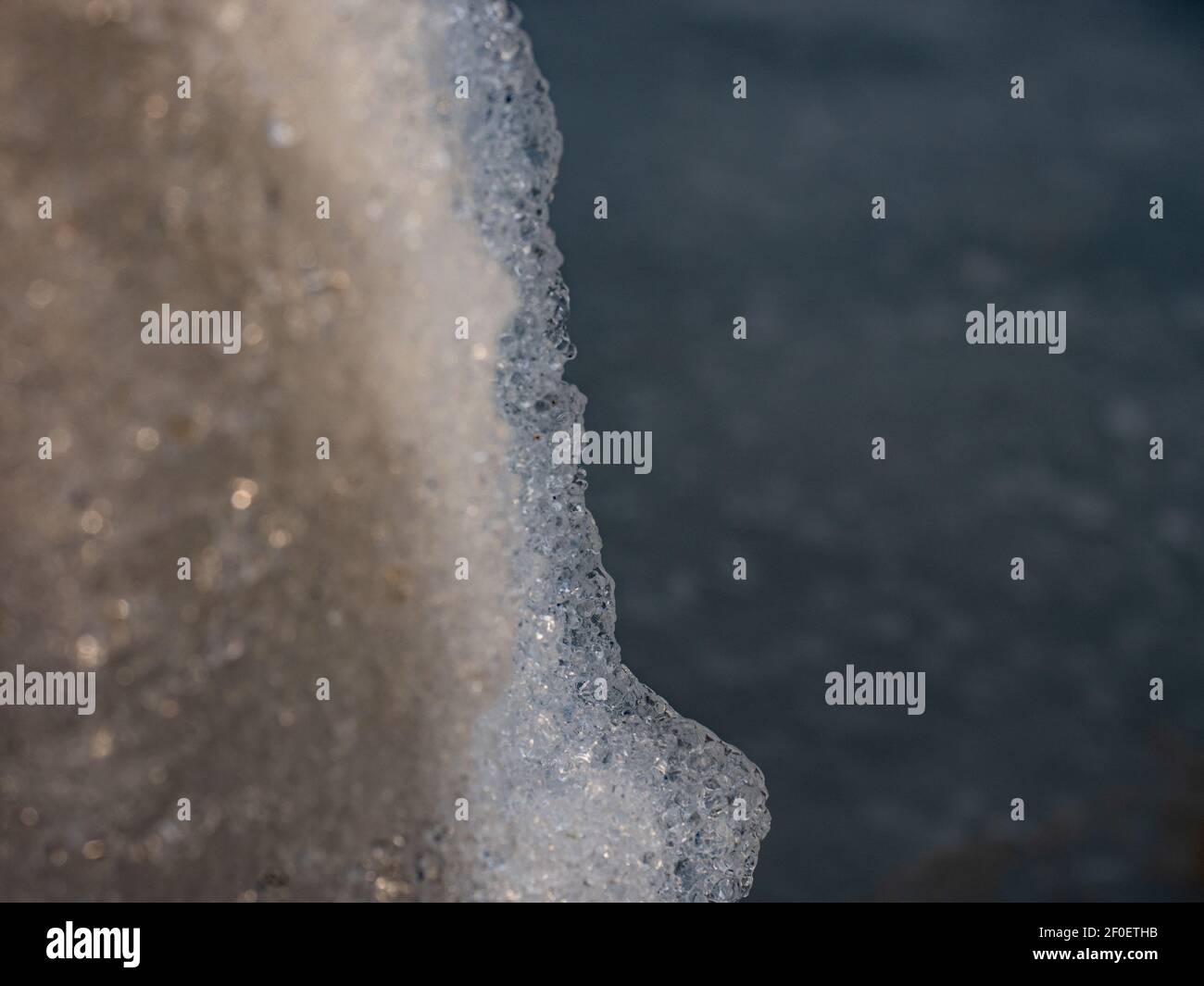 Smashed ice melts in the water on the edge of the beach. Large icebergs ...