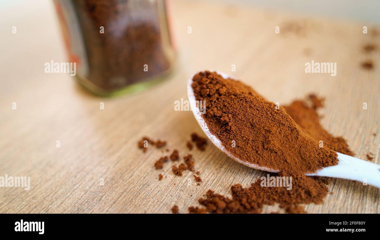 Coffee powder in the Spoon isolated on table wooden background. Pile of ...