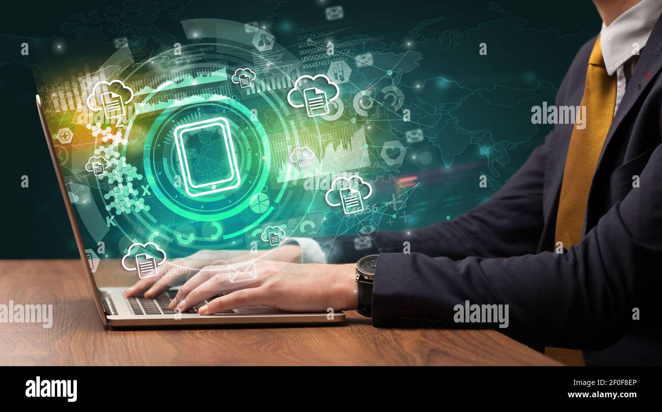 Business hand typing on a modern laptop with tablet icon coming out ...