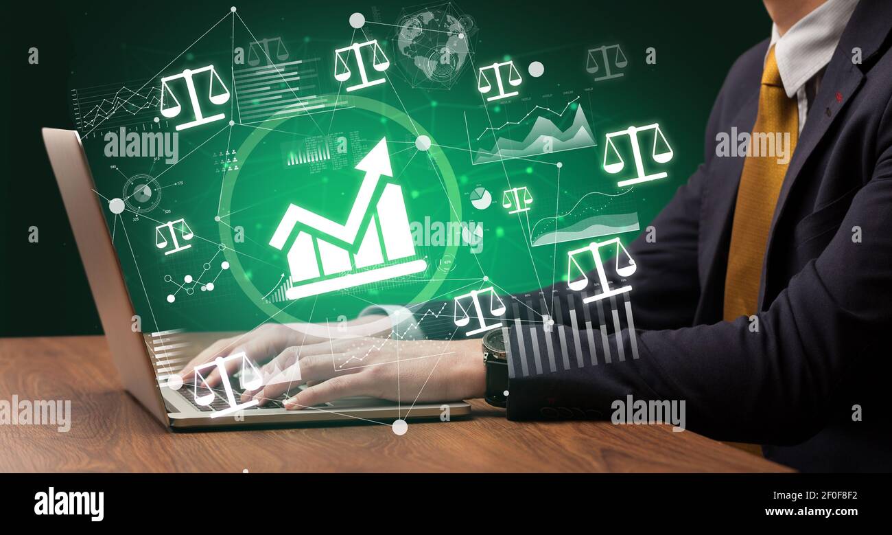 Business hand working on laptop with diagram icons coming out from the ...