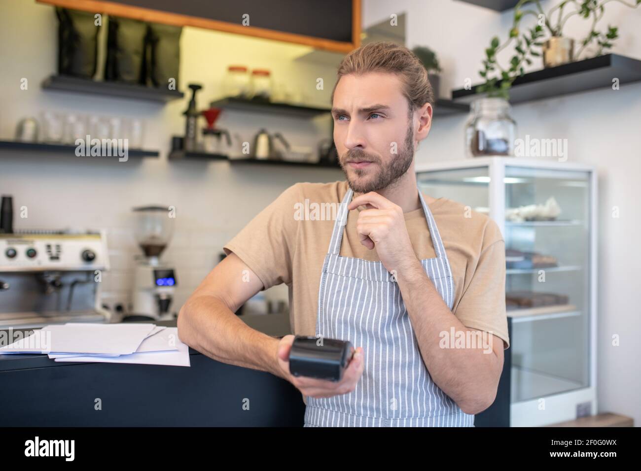Man mentally counting standing with terminal in cafe Stock Photo - Alamy