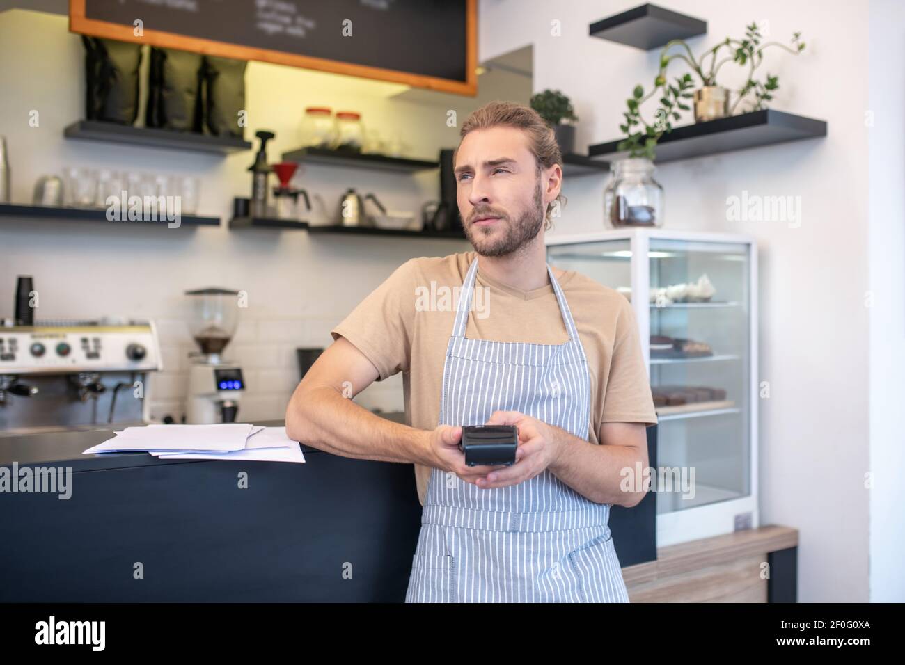 Thinking man with pos terminal in his hands Stock Photo - Alamy