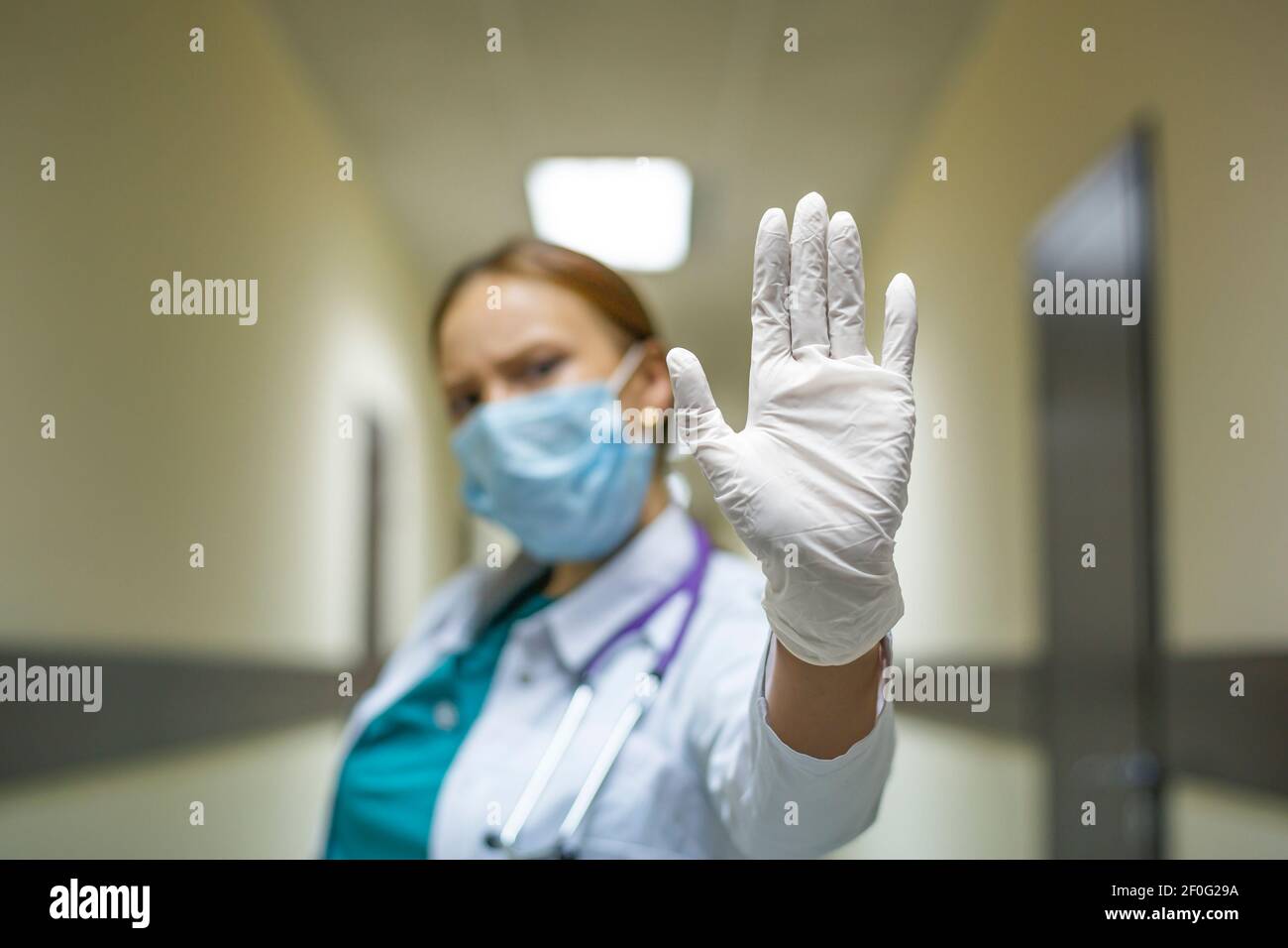 Woman doctor in the hospital corridor. She shows the stop sign with the ...