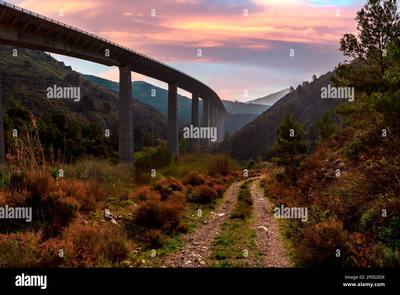 Landscape of a long viaduct through the middle of a valley at sunset ...