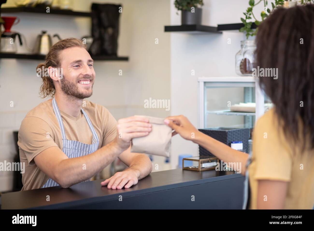 Man at counter giving package to woman Stock Photo - Alamy