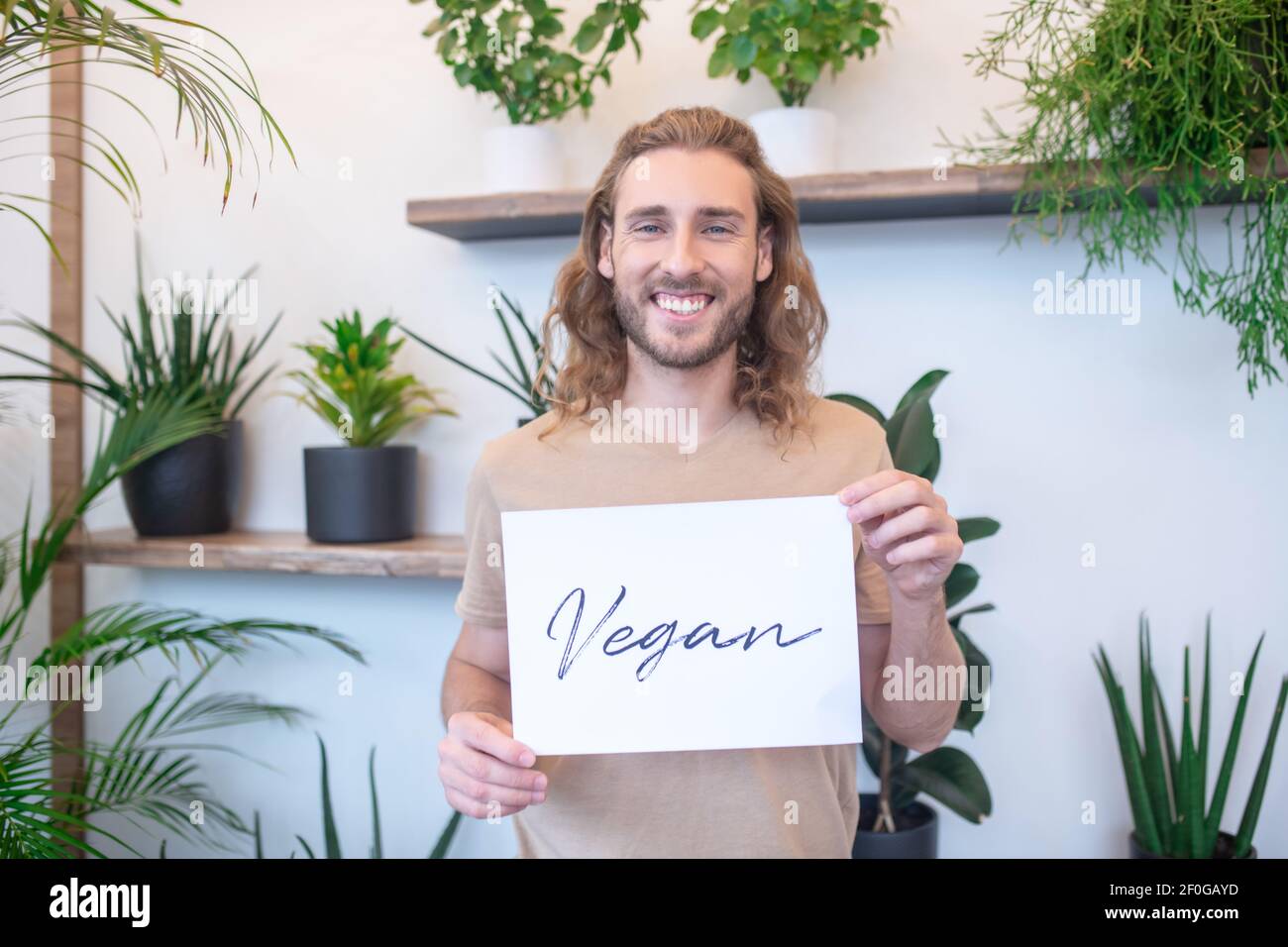 Happy man holding poster with word vegan Stock Photo - Alamy