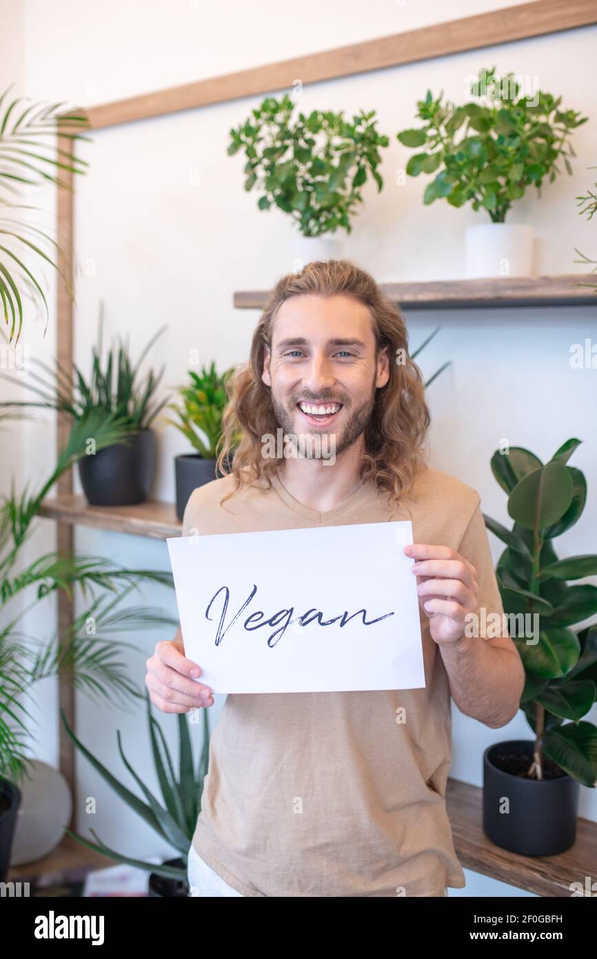 Good looking young man standing indoors with placard Stock Photo - Alamy
