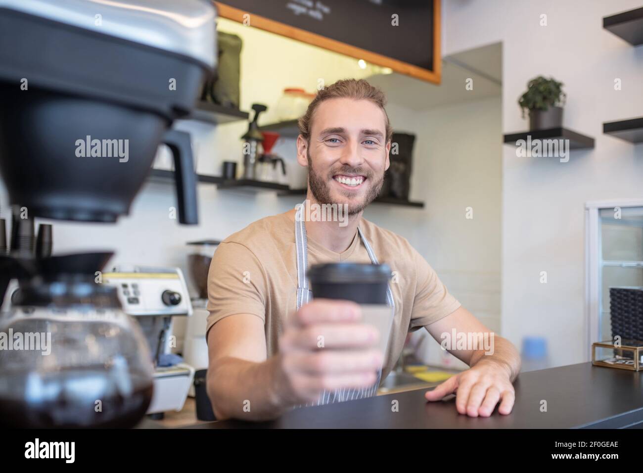 Barista with glass of coffee behind cafe counter Stock Photo - Alamy