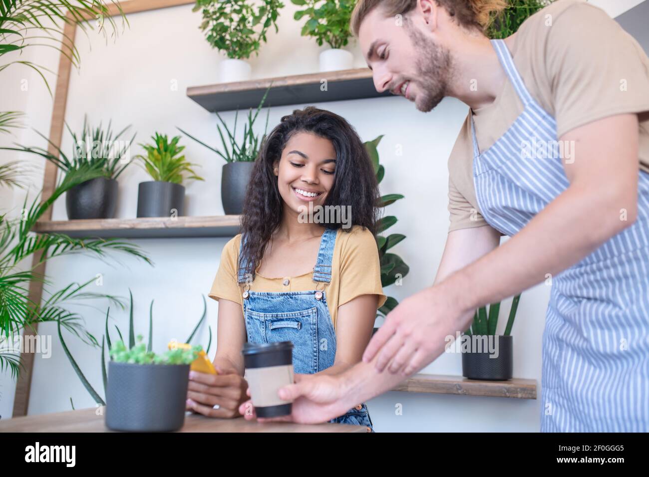 Barista giving glass of coffee to woman at table Stock Photo - Alamy