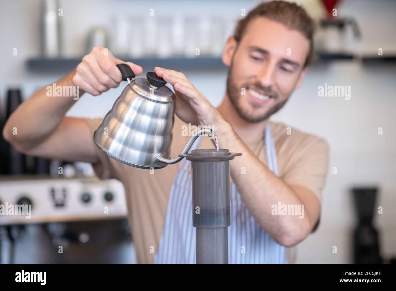 Joyful male barista with teapot pouring water Stock Photo - Alamy