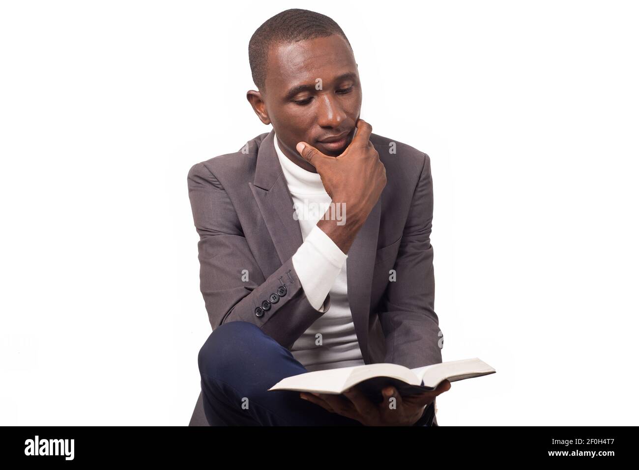 portrait of young pastor sitting cross-legged, hand under chin and ...